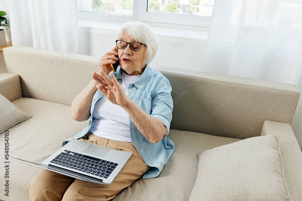 busy with work, a serious elderly businesswoman is sitting on a cozy ...