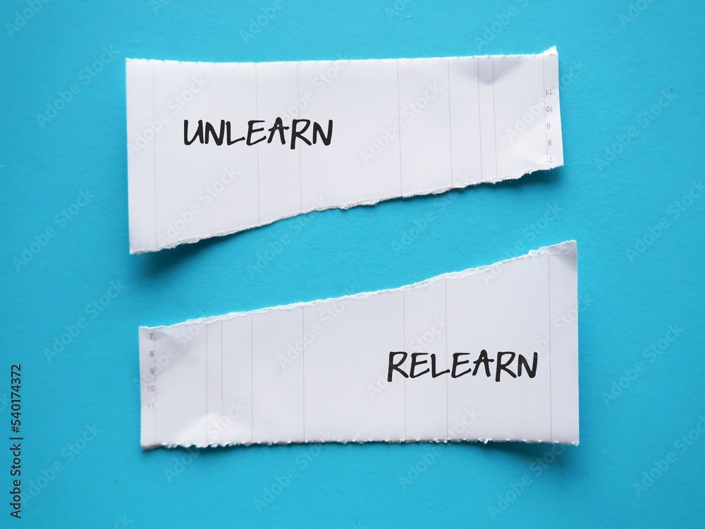 Torn note paper on blue background with handwritten text Unlearn and ...