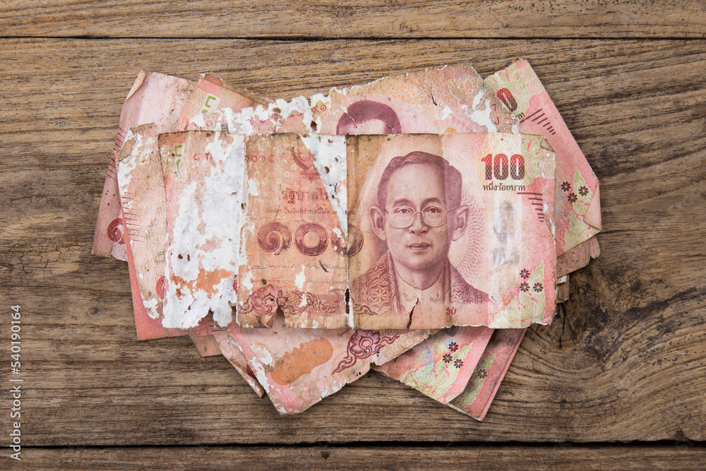 Thai 100 baht banknotes torn, damaged, decayed on the old wooden floor ...