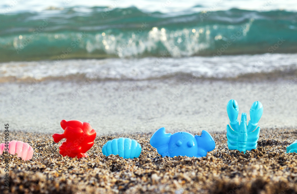 sands beach toys in a row against sea water and kid little boy is ...