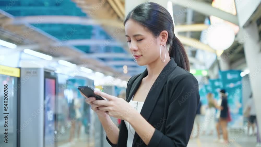 Beautiful asian working woman using smartphone while waiting for the train at Skytrain subway ...
