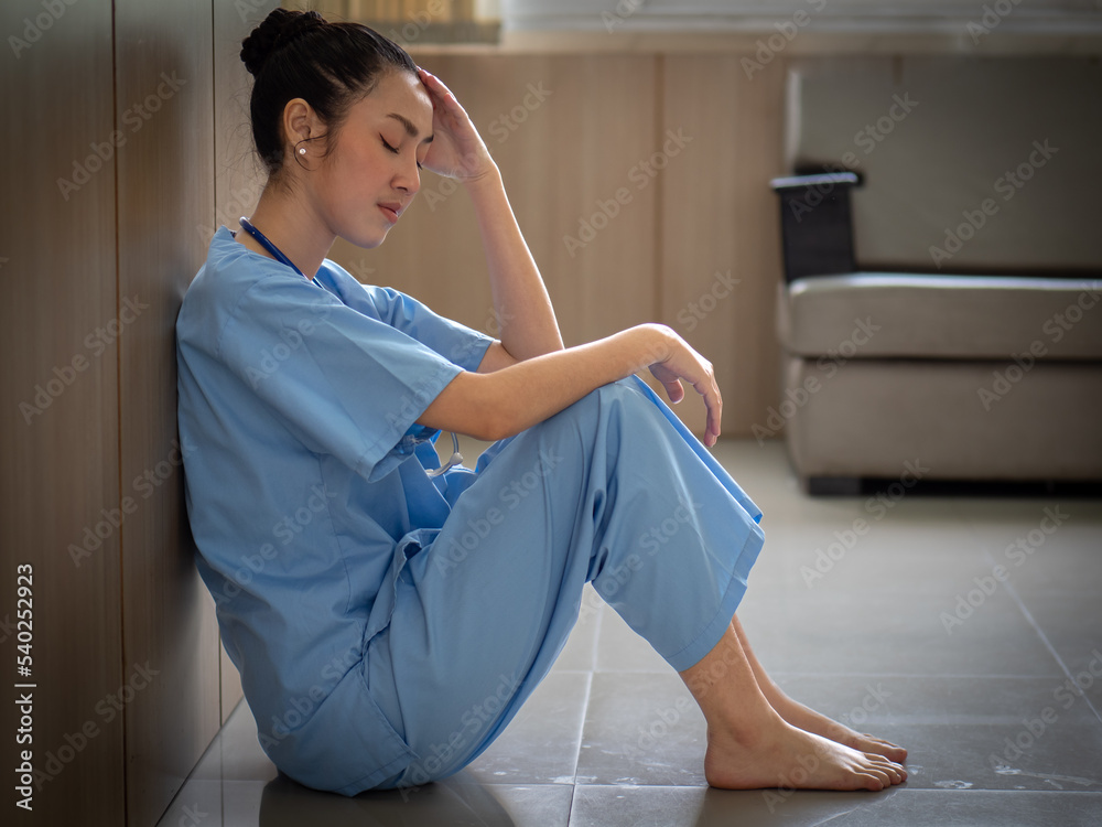 Overworked female doctor sitting on the floor in hospital despair ...