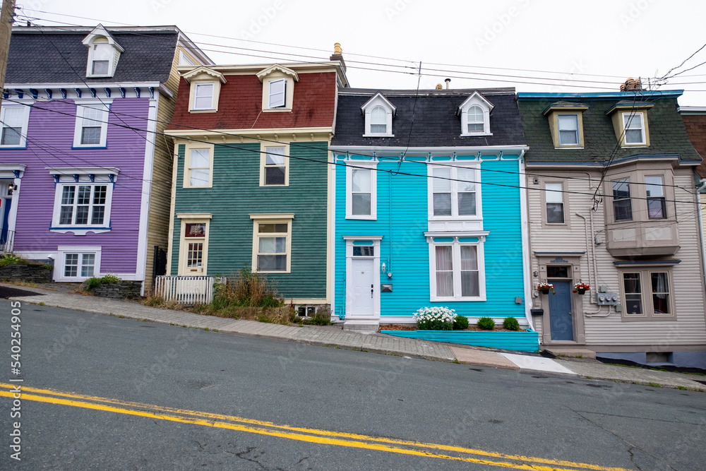 Brightly colored wooden row houses with a blue sky in the background ...
