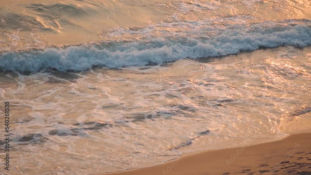 High angle slow motion shot of sea waves on the beach during the sunset ...
