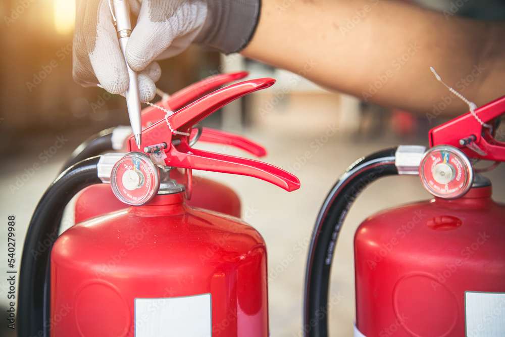 Close up fire extinguisher and firefighter checking pressure gauge ...