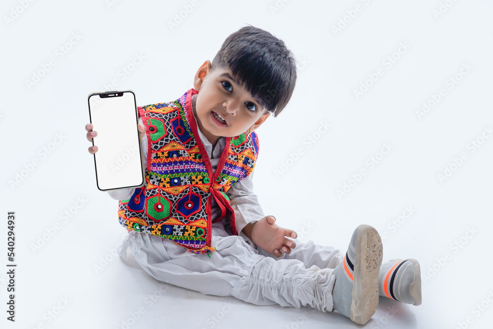 cute indian little kid in ethnic dress playing with phone or showing ...