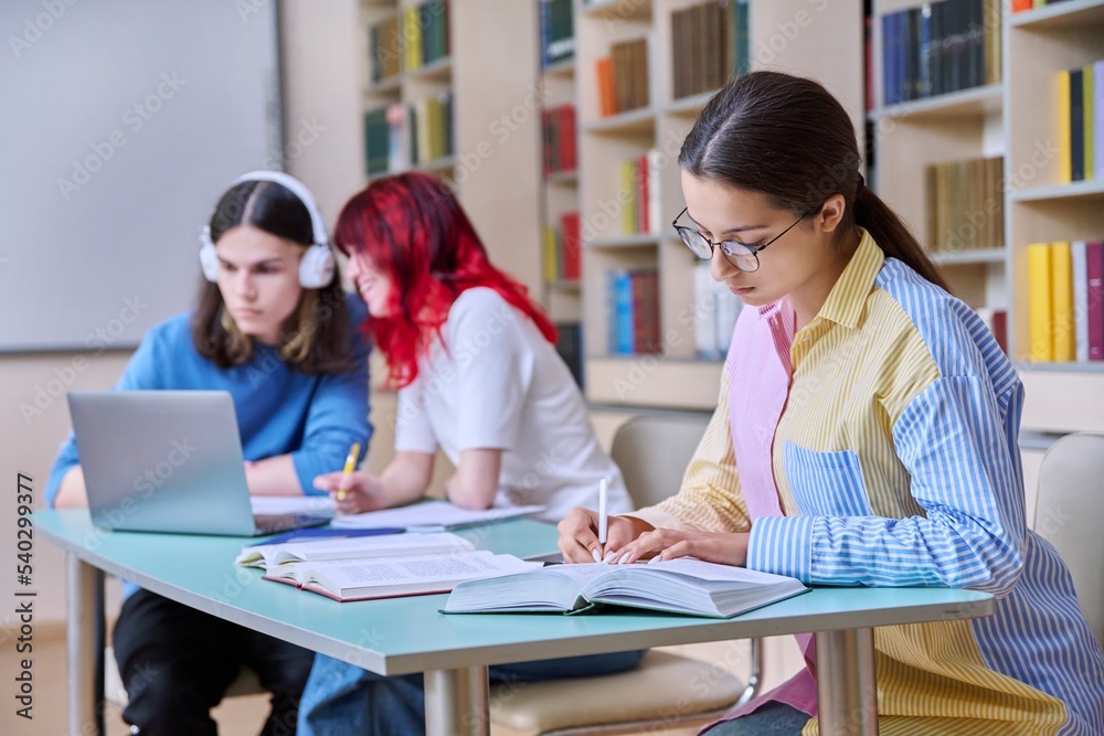 High school students studying in library class, teenage girl in focus ...