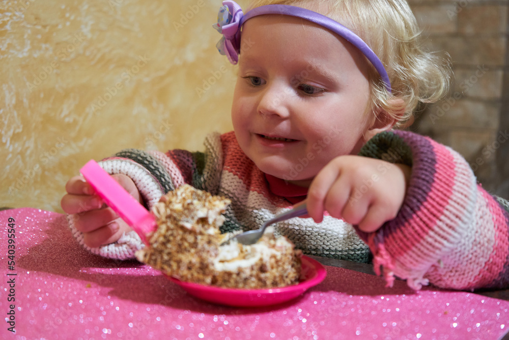 happy little girl eating cake,the child tastes the birthday cake at the ...
