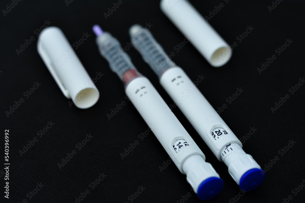 Insulin pen isolated on black background. Medical devices are used for ...