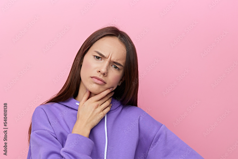 a sullen woman stands full-face on a pink background in a purple suit ...