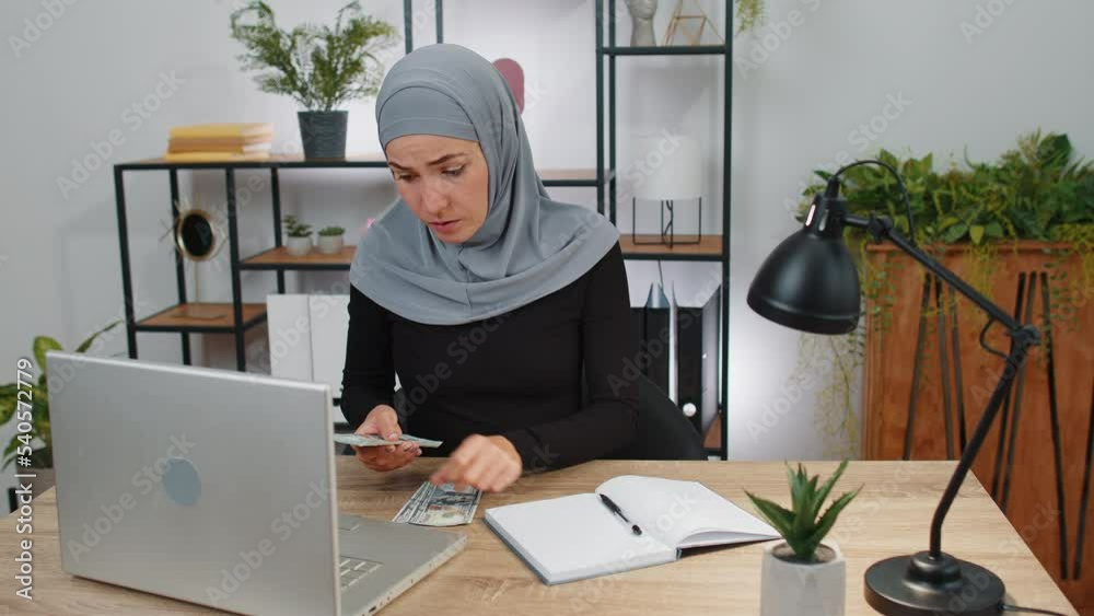 Rich business woman in hijab working on laptop pc counting money cash ...
