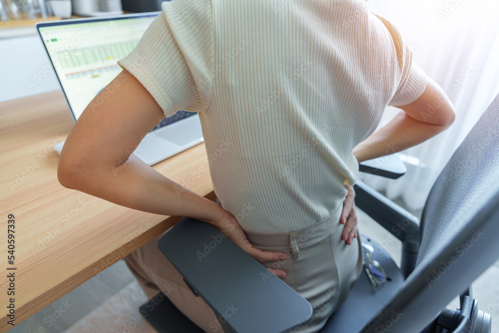 Woman having back body pain during work long time on workplace. due to ...