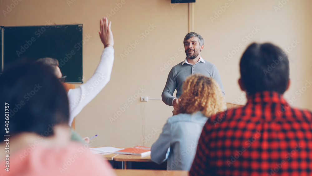 Friendly male teacher is talking to his students checking knowledge ...