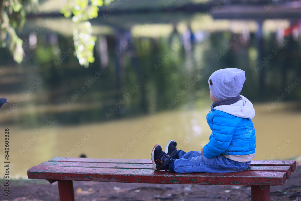 boy child is sitting on a park bench walking Stock Photo | Adobe Stock
