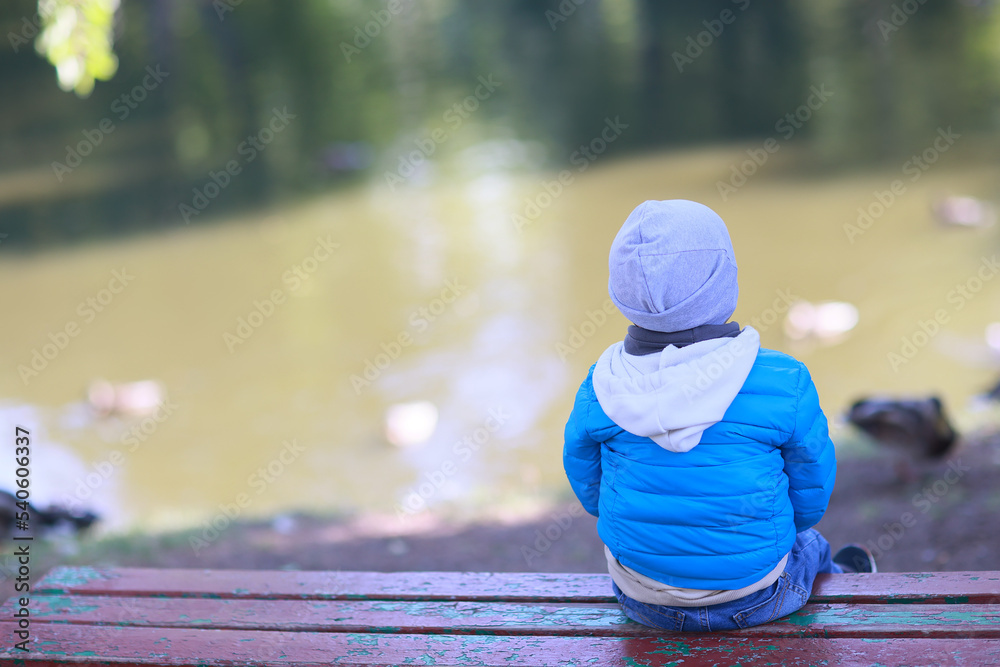 boy child is sitting on a park bench walking Stock Photo | Adobe Stock