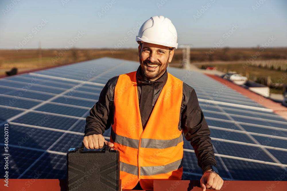Happy worker done his job with solar panels and he is holding toolbox ...