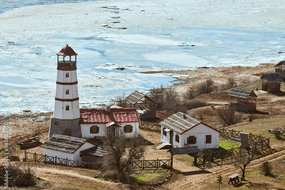 Beautiful white red lighthouse with farm utility houses in Merzhanovo ...