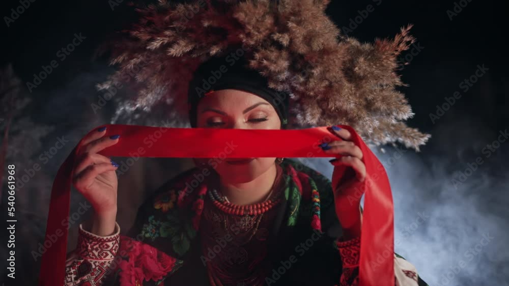 Ukrainian woman ties red ribbon around eyes as on ritual doll motanka ...