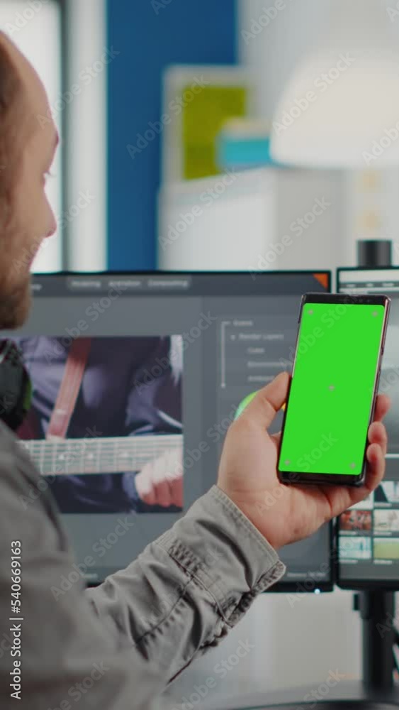 Video editor talking on video call holding smartphone with green screen ...
