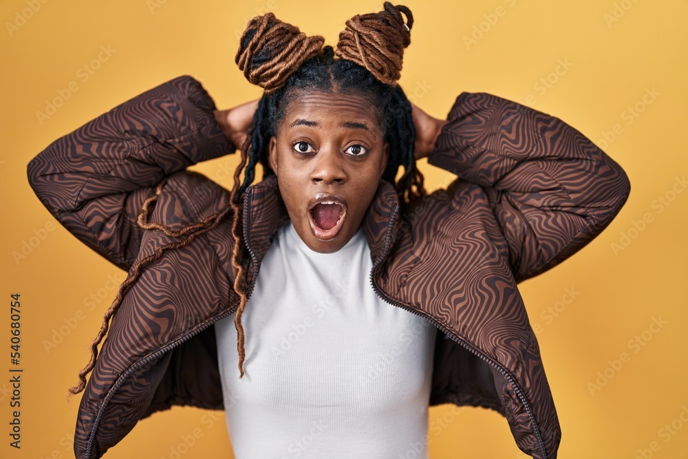 African woman with braided hair standing over yellow background crazy ...