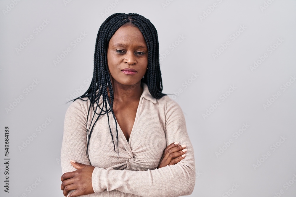 African woman with braids standing over white background skeptic and ...