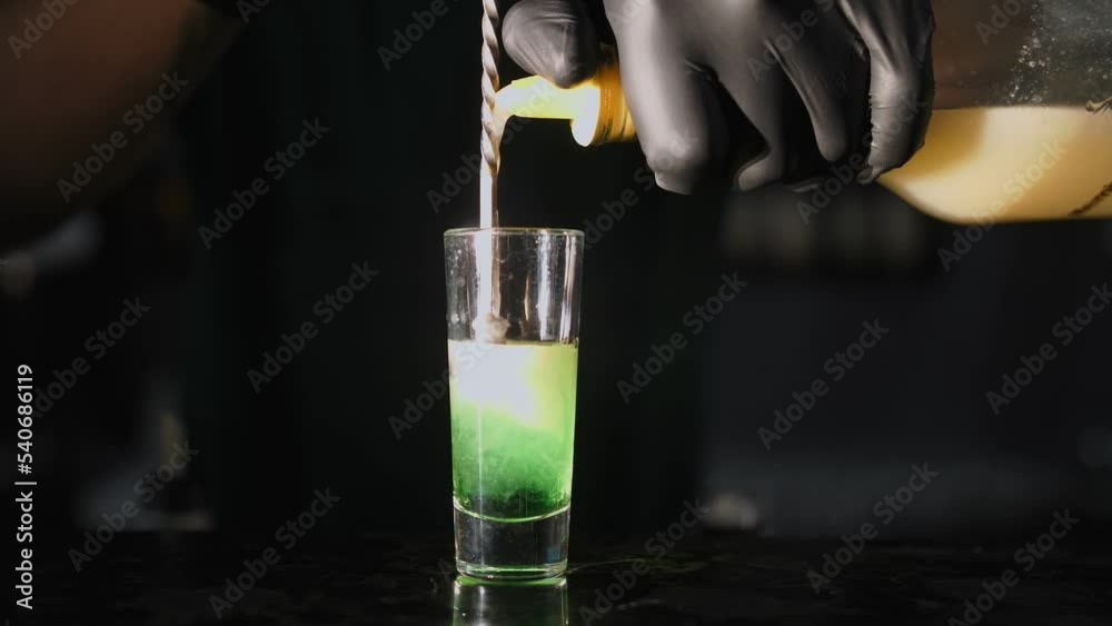 Cocktail Shots. close-up. bartender is pouring different alcoholic drinks in layers, into shot ...