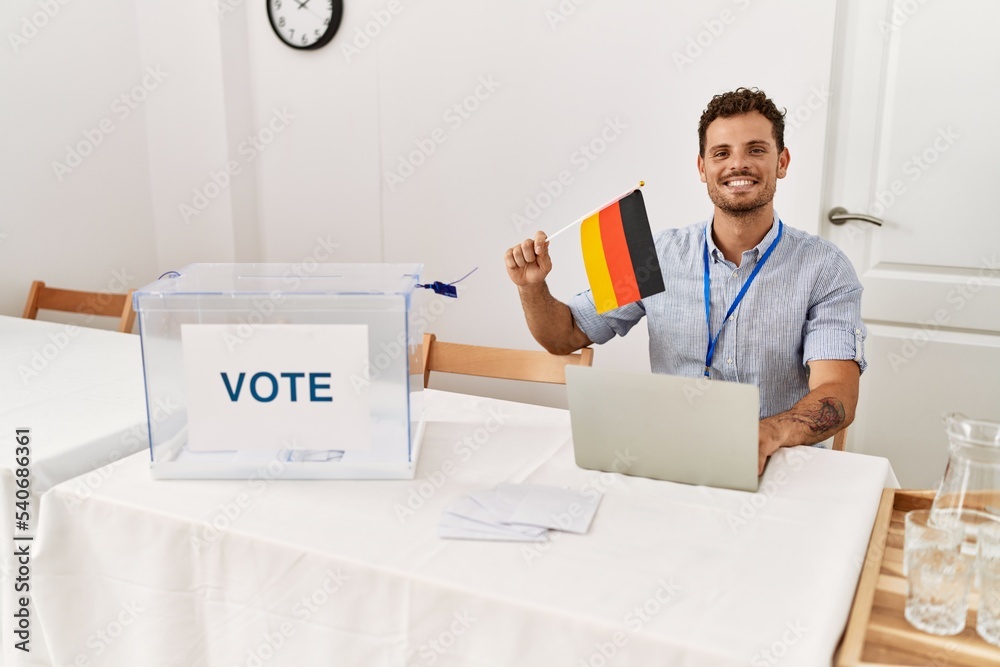 Young hispanic man smiling confident holding germany flag working at ...