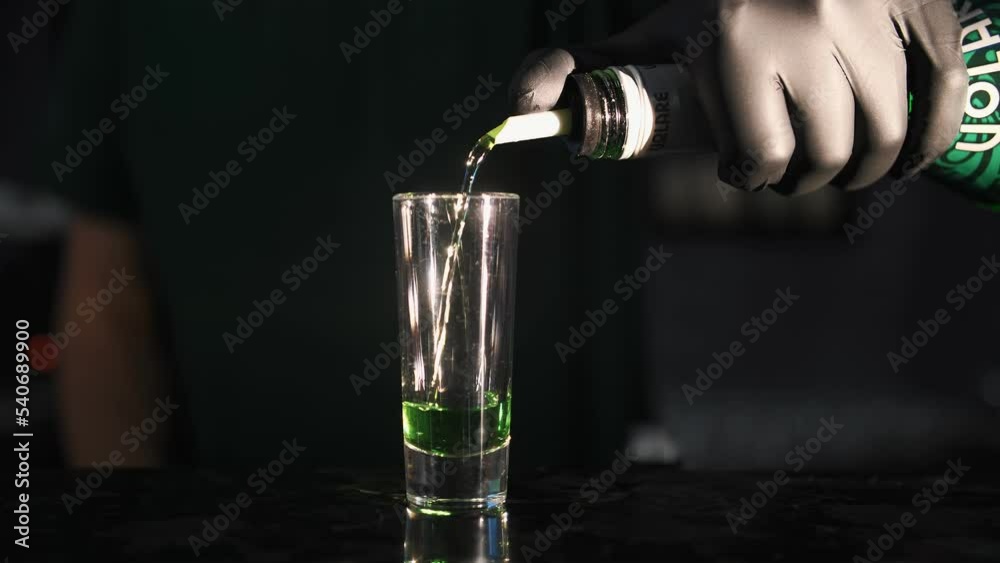 Cocktail Shots. close-up. bartender is pouring different alcoholic drinks in layers, into shot ...