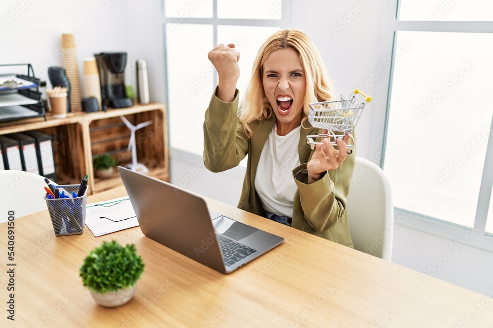 Beautiful blonde woman doing online shopping holding supermarket cart ...