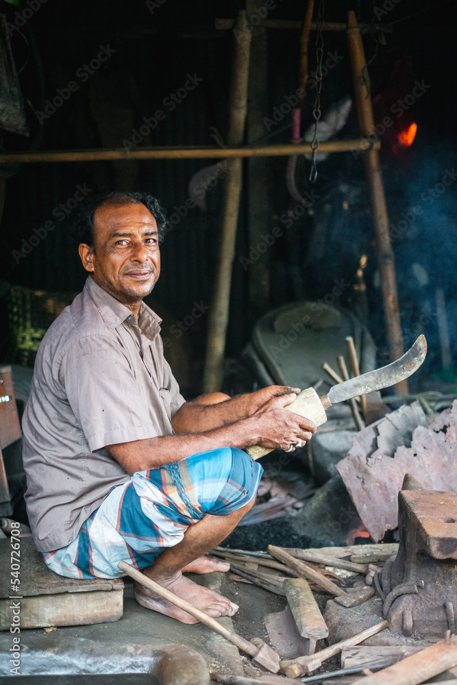 South asian village blacksmith with traditional dress and equipments ...