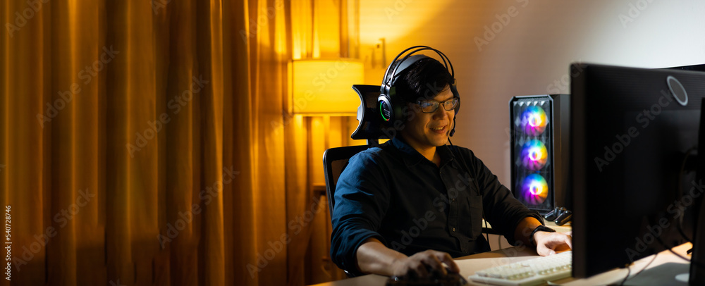 Happy Professional Asian male gamer playing video games on personal pc ...