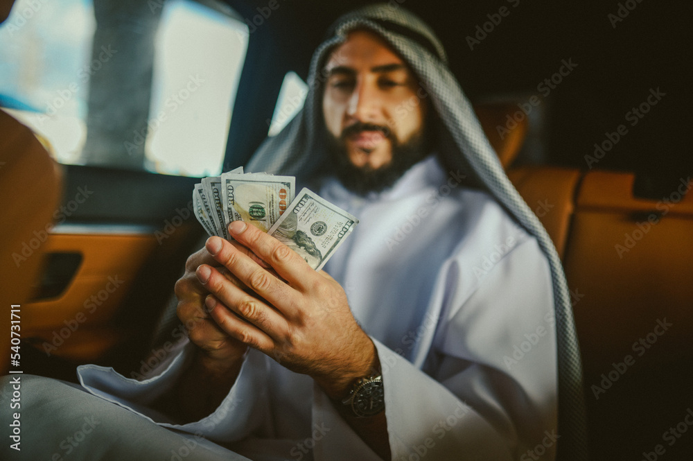 An arabian man in a traditional clothing in a car holding money Stock ...