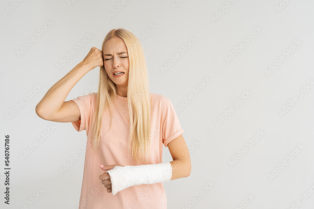 Studio portrait of suffering young woman with broken arm wrapped in ...