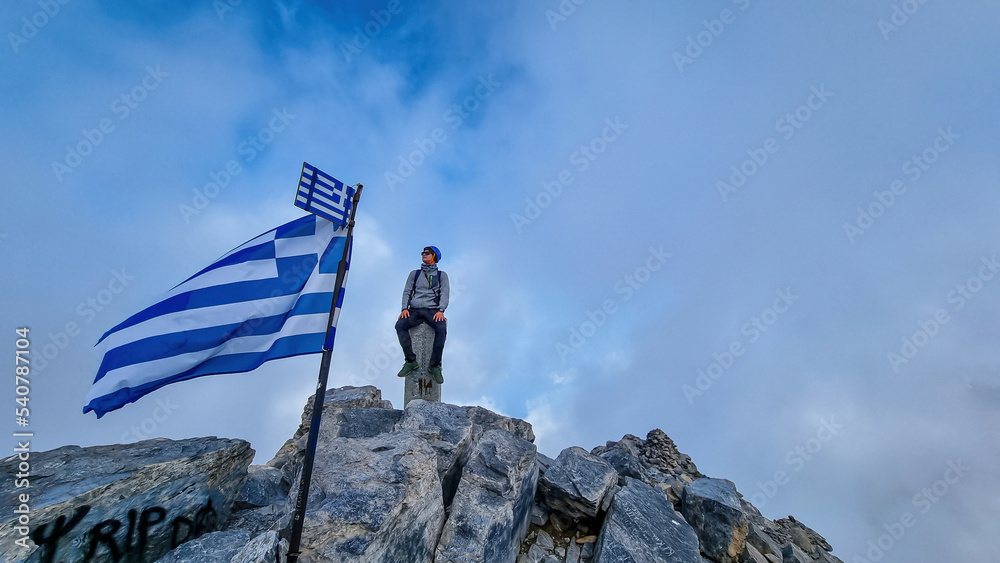 Happy man with climbing helmet sitting on cloud covered mountain summit ...