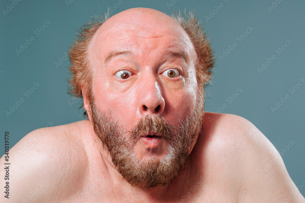Front view in the studio portrait of an elderly man grimacing at the ...