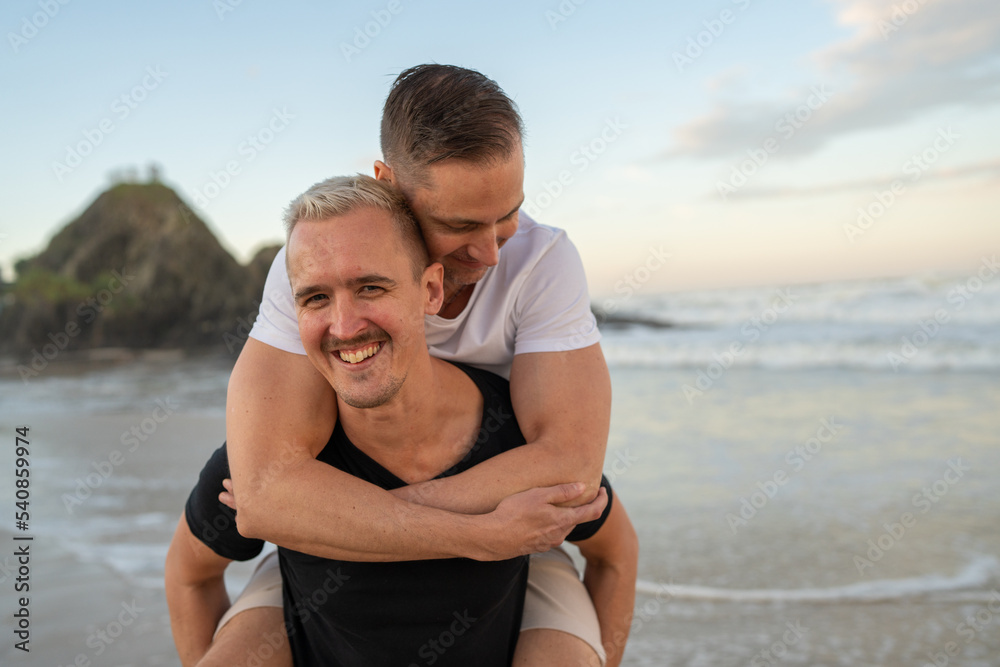 gay couple with cuddle from behind on beach and fairy floss sky Stock ...