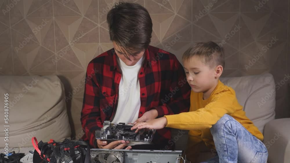 A teenager holds a motherboard for a computer in his hand and shows it ...