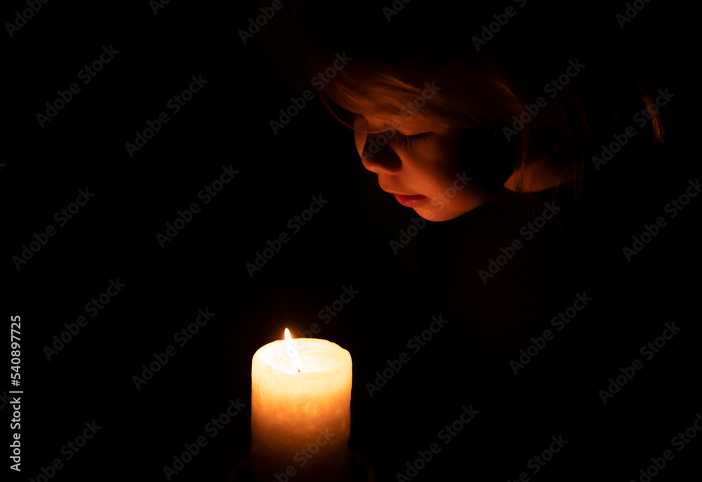 child looks fascinated from above at the burning flame of a candle in a ...