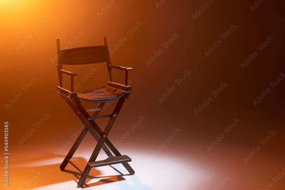 The director's chair stands in a beam of light with an orange backlight ...