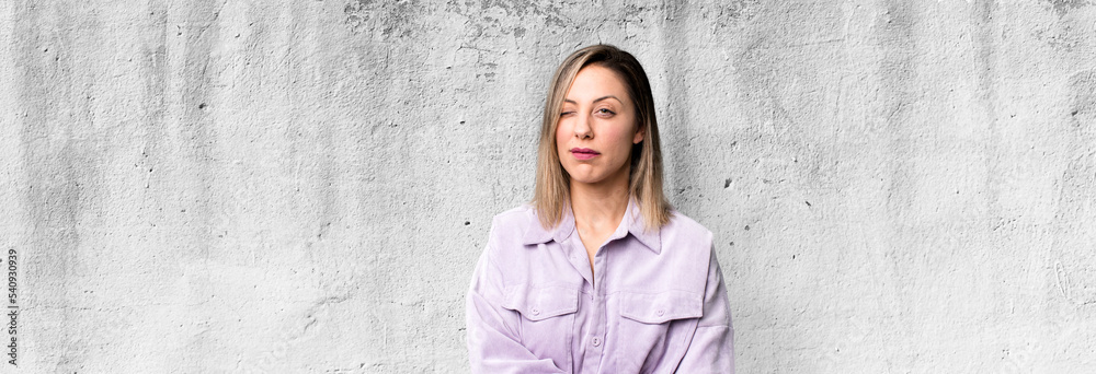 blonde adult woman looking happy and friendly, smiling and winking an ...