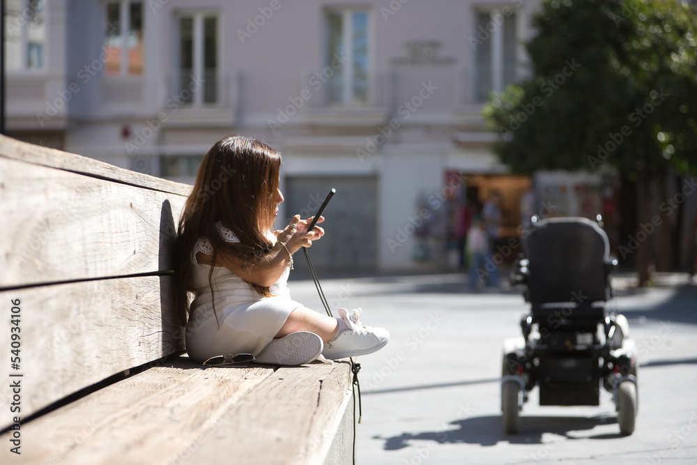 Disabled woman with reduced mobility and small stature sitting on a ...