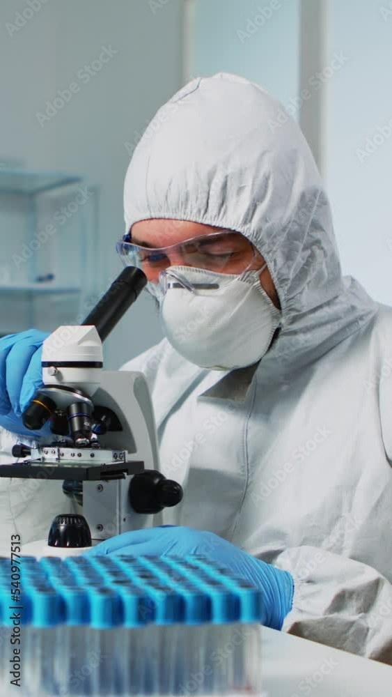 Vertical video: Medical research scientist in ppe suit conducting ...