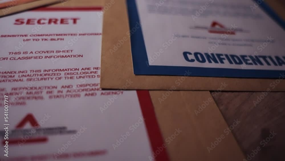 Pan across top secret classified manila folders containing sensitive ...