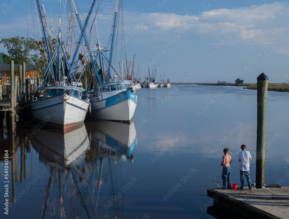 Shrimp boats at moorage, Darien, GA, Two boys fishing from a floating ...