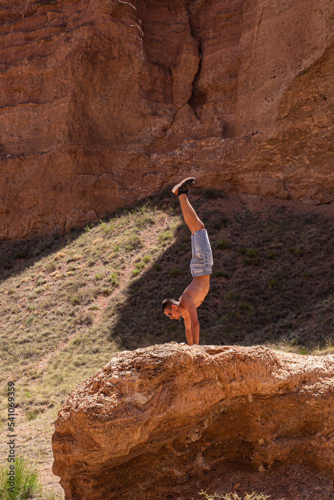 Foto de a man of athletic build performing a handstand on a large rock ...