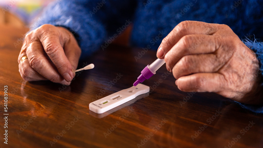 Old woman placing the sample into the covid-19 antigen diagnostic test ...