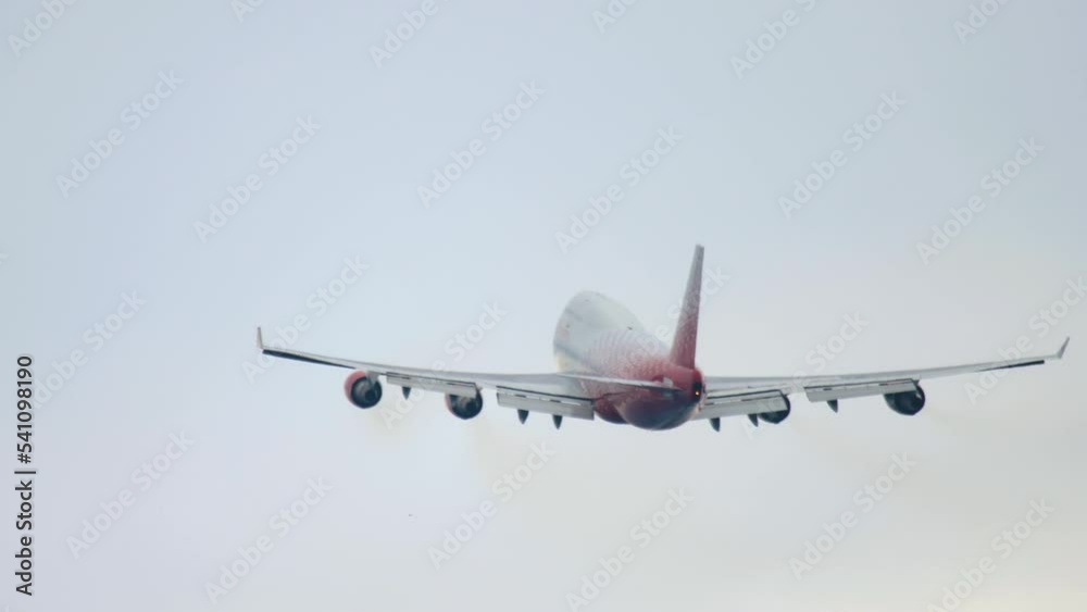 Wide body climb after takeoff, flies away, rear view long shot ...