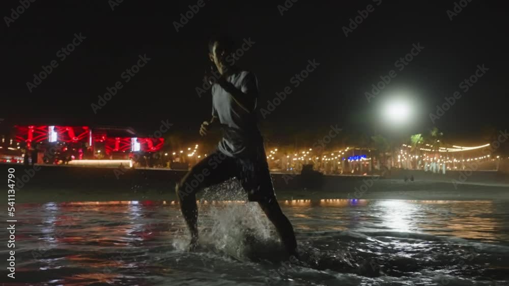Attractive male dancer performing dancing movements standing in ocean ...