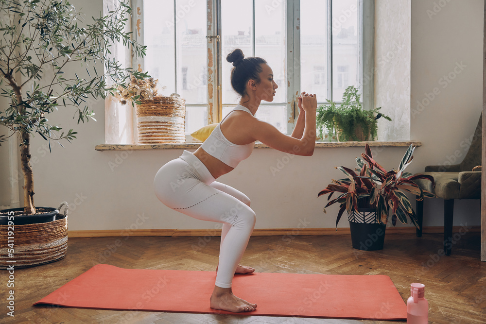 Confident woman standing in squatting position while practicing in ...