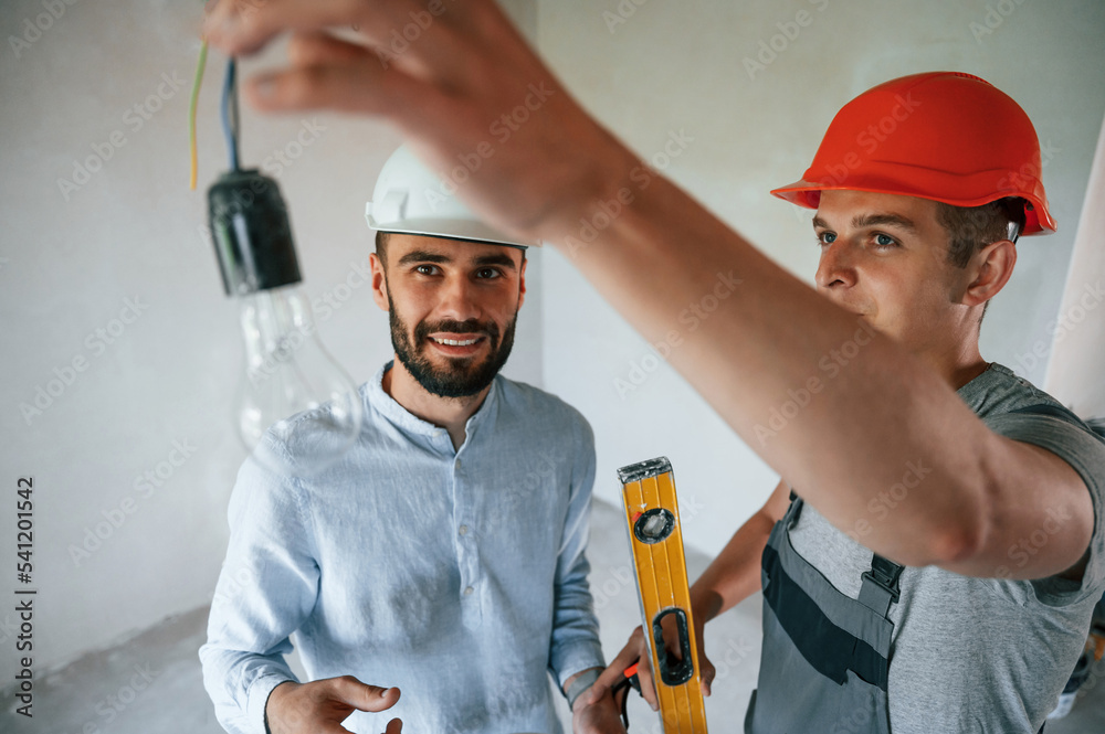 Working with light bulb. Two men is making repairs in the apartment ...